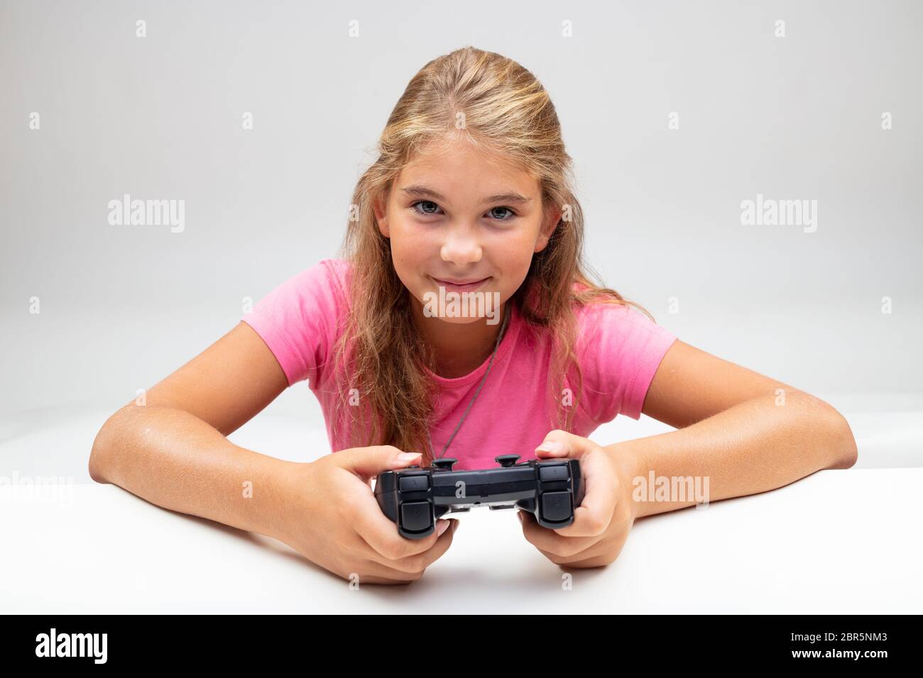 Pretty little girl holding a gaming console in her hands as she leans ...
