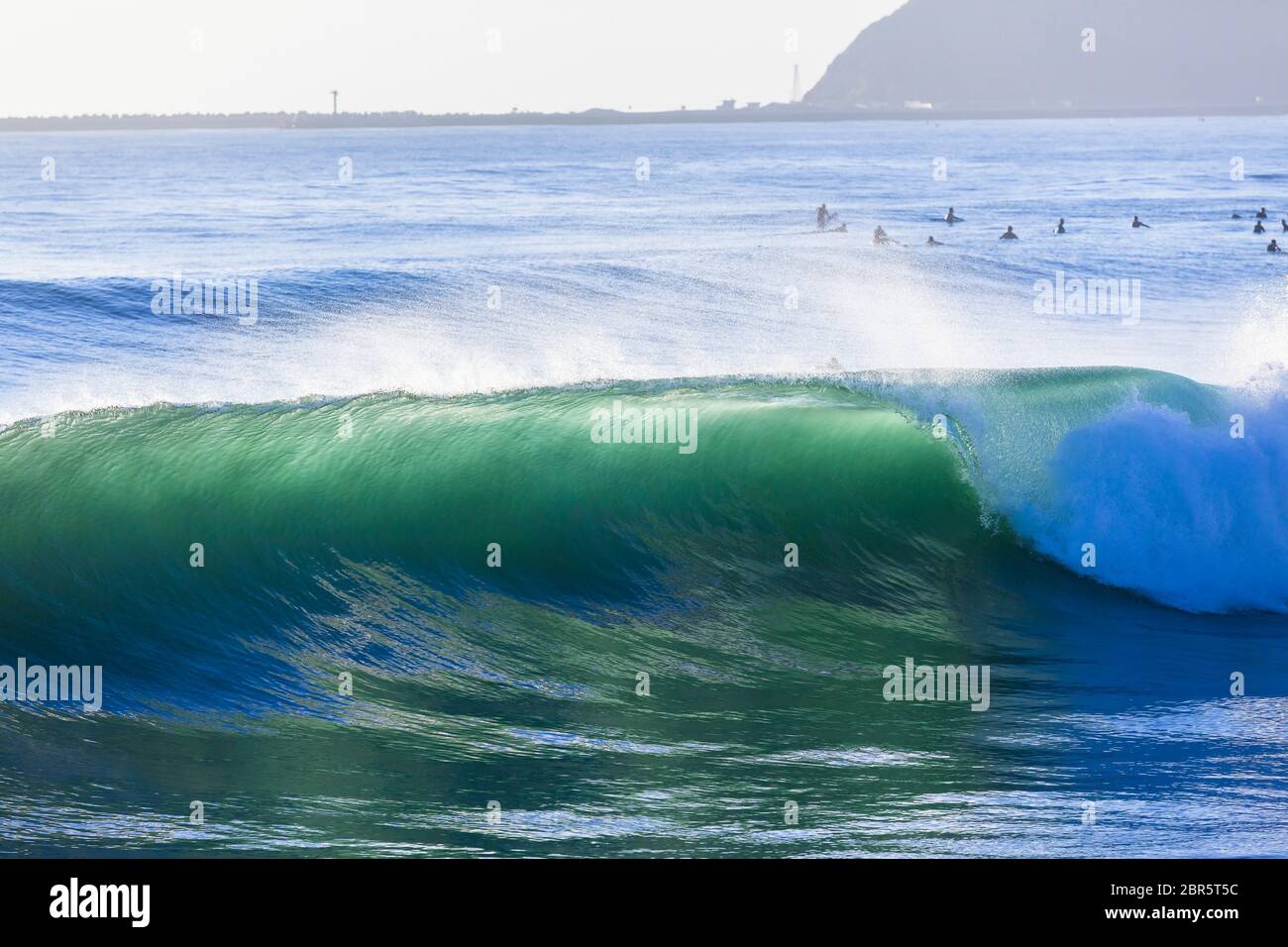Wave ocean wall crashing with surfers paddling Stock Photo - Alamy