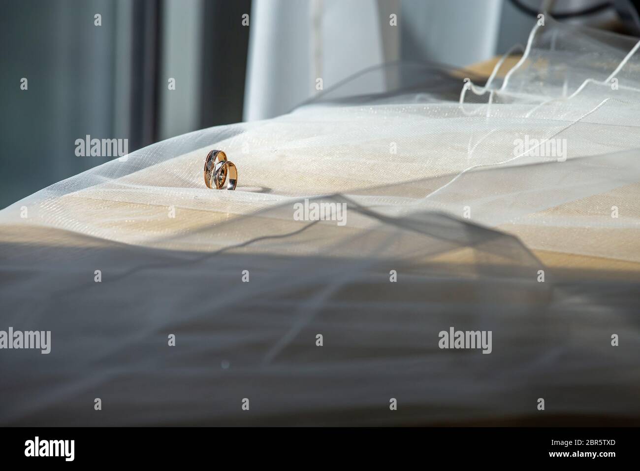 Two wedding rings on wedding veil. Gold wedding rings on the background ...