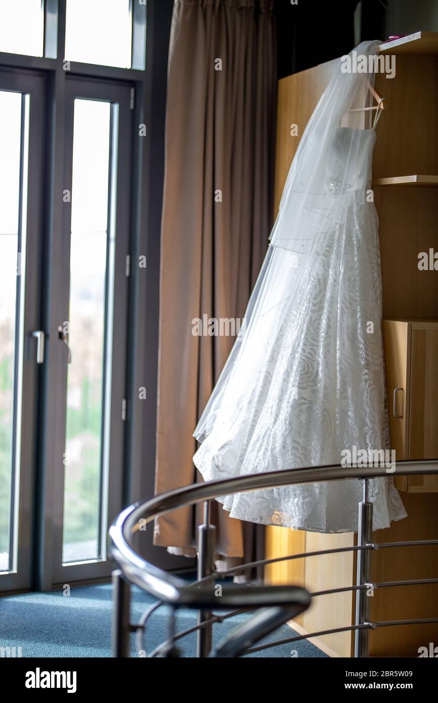 White wedding dress hanging at wooden closet. White bridal dress on the ...