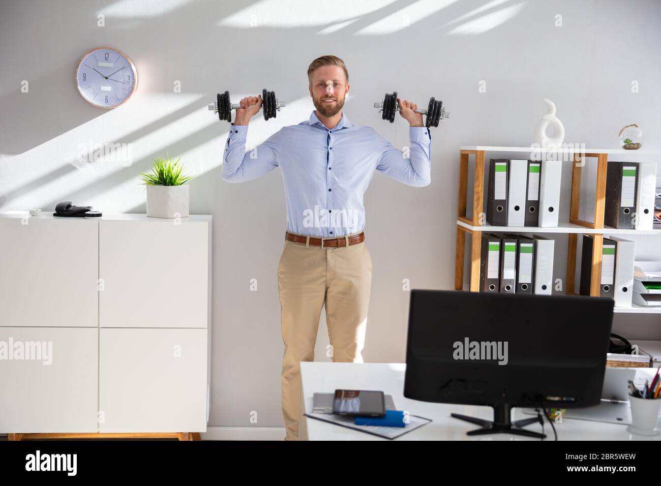 Attractive Businessman Exercising With Dumbbells In Office Stock Photo ...