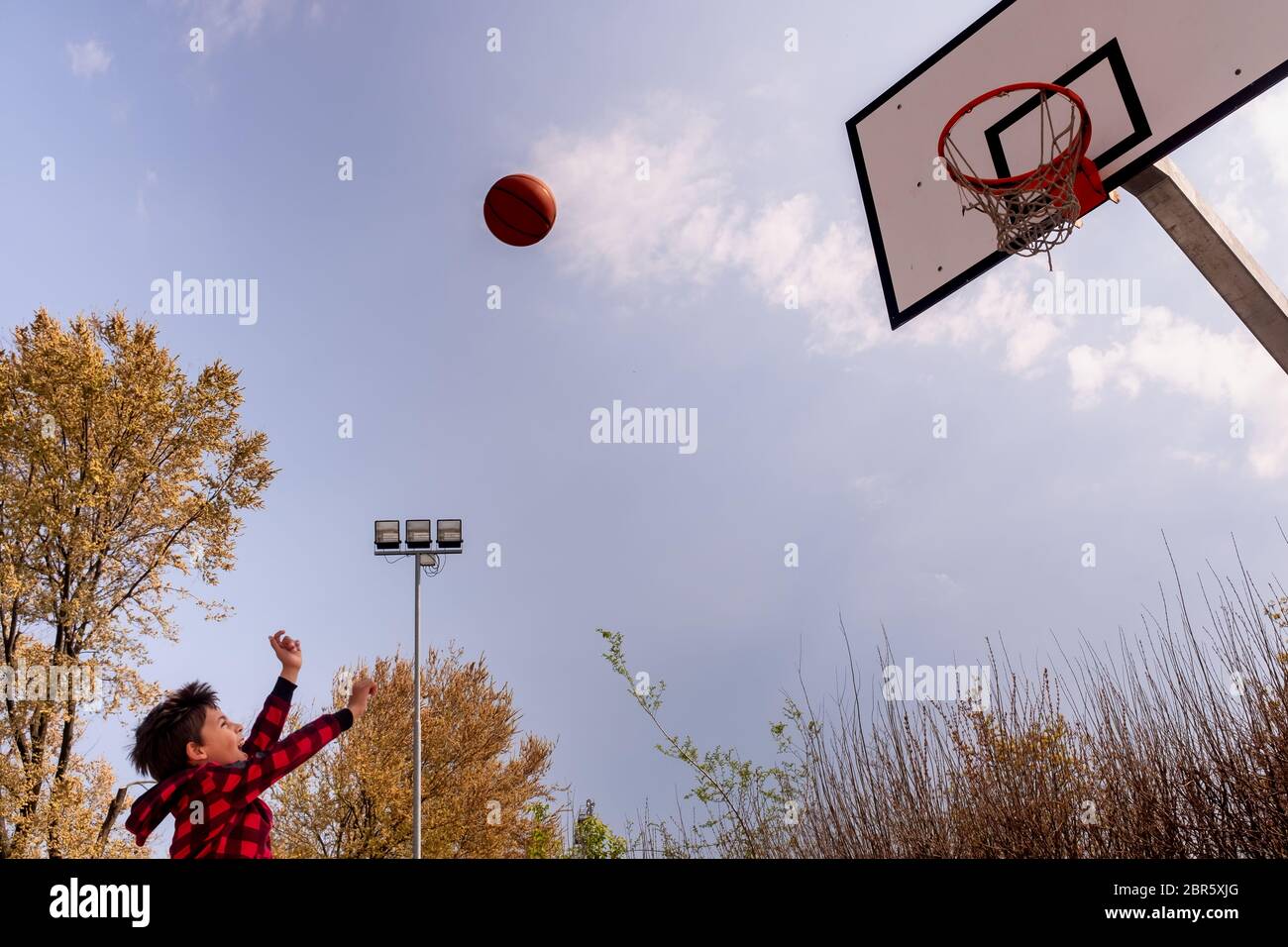 Body part of dynamic young boy with arms raised shooting a basket ball ...