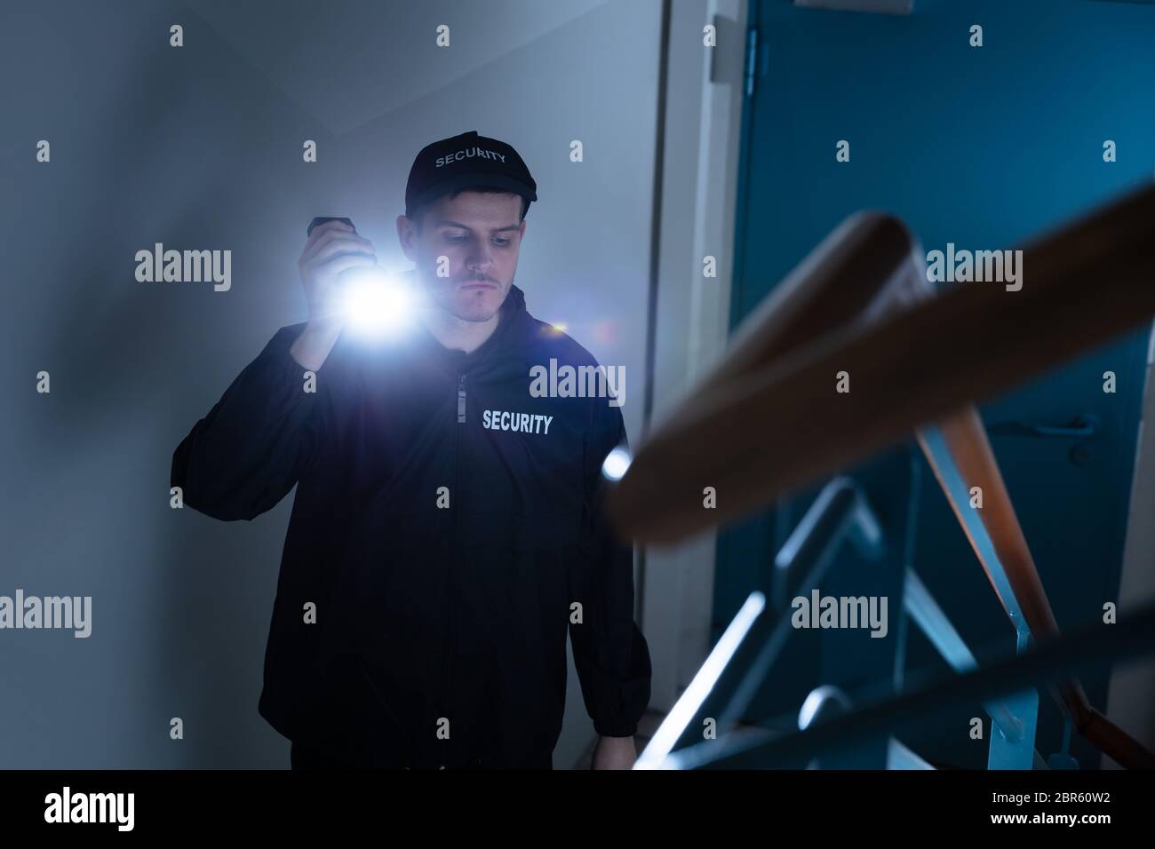 Male Security Guard Standing On Staircase Holding Flashlight Stock ...