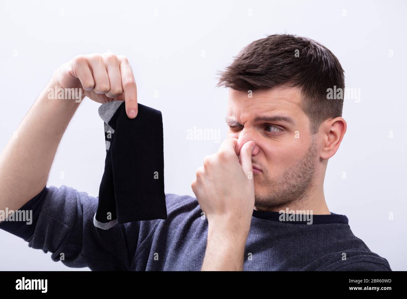 Young Man Holding His Stinking Socks Against White Background Stock ...