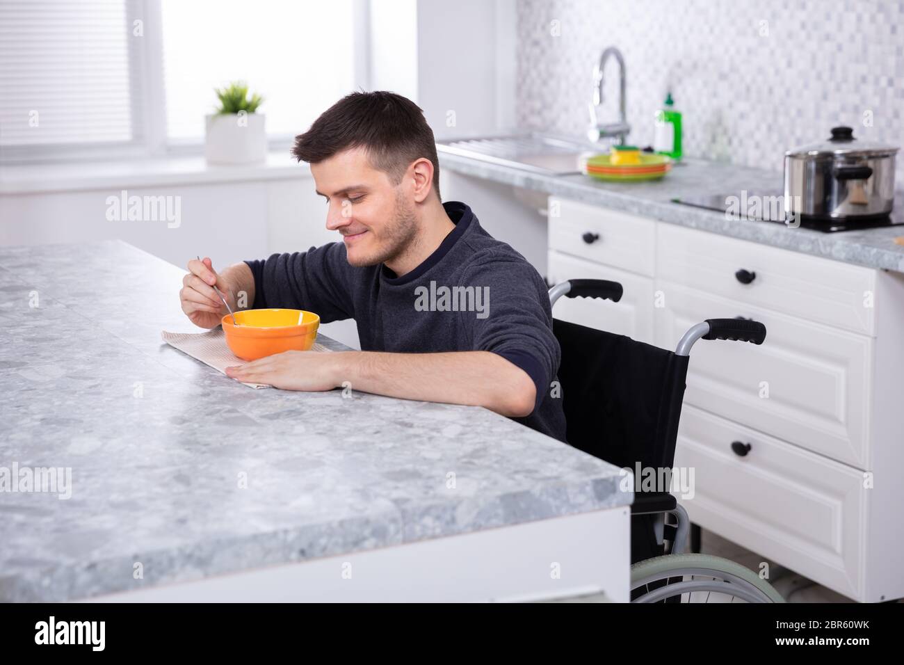 Smiling Disabled Young Man Sitting On Wheelchair Drinking Soup In The ...