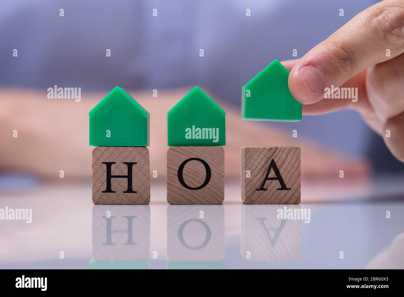 Businessman's Hand Placing House Models On Wooden HOA Cubic Blocks Over ...