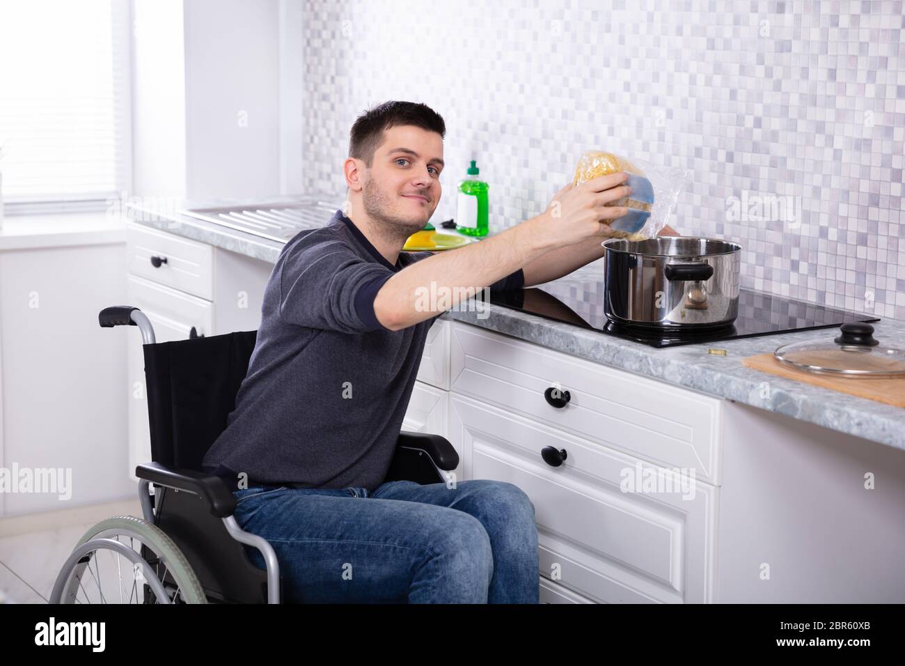 Smiling Young Handicapped Man Sitting On Wheelchair Preparing Food In ...