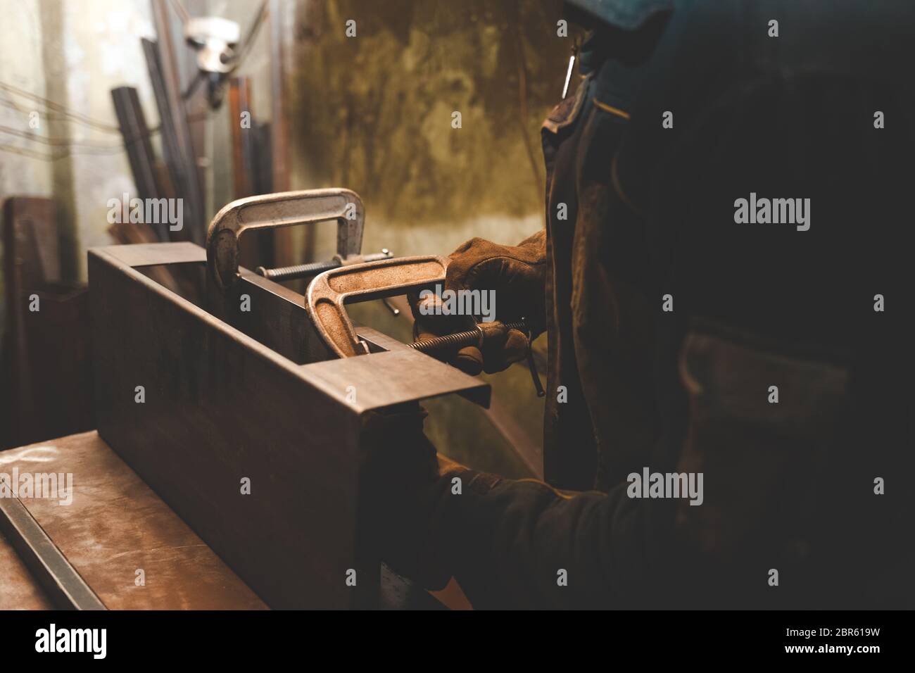Man clamps iron products into c-clamps. Man works with clamps. Steel ...