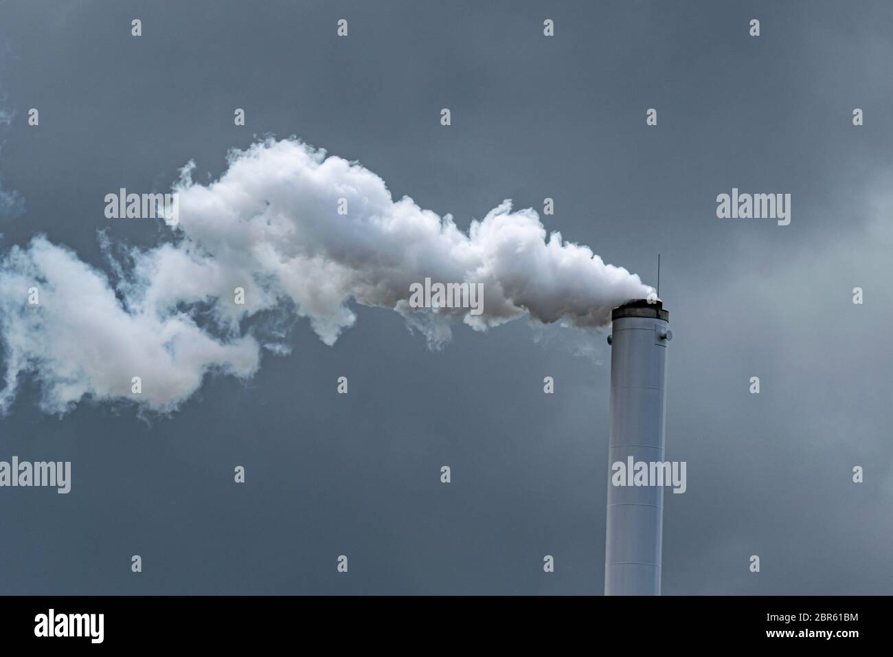 Smoking chimney from garbage factory against a dark sky close-up ...