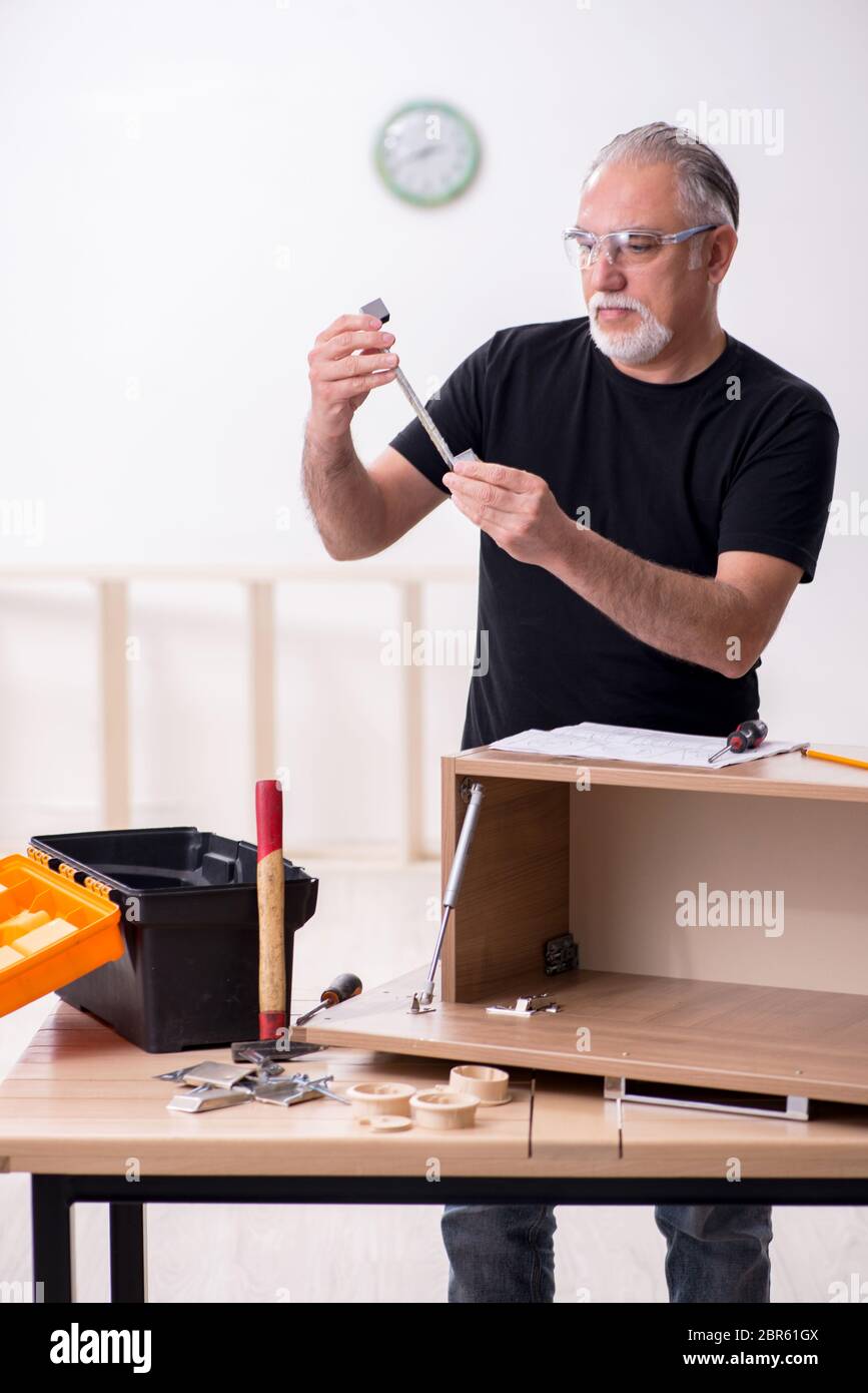 Old carpenter working indoors on furniture Stock Photo - Alamy