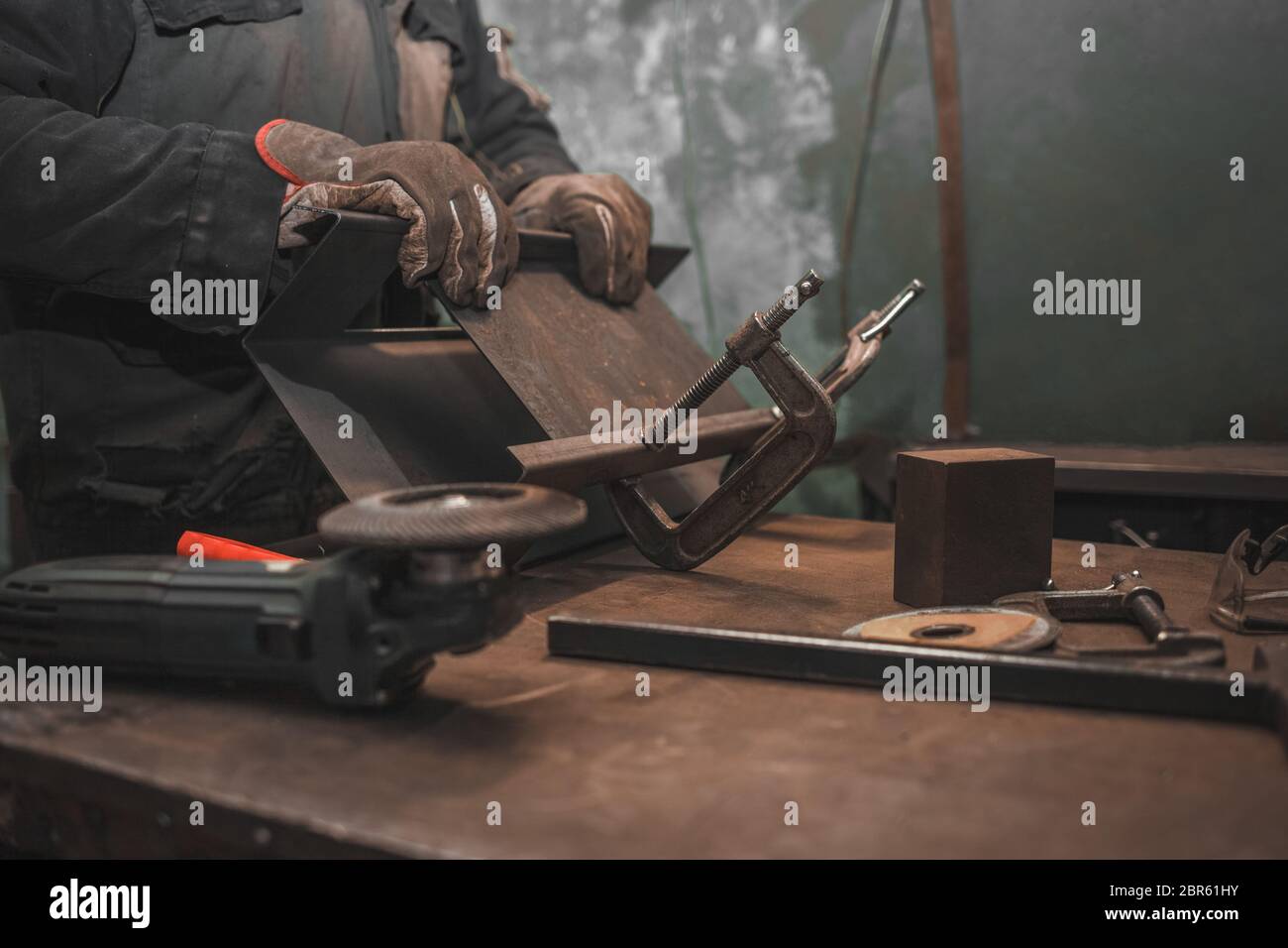 Man clamps iron products into c-clamps. Man works with clamps. Steel ...