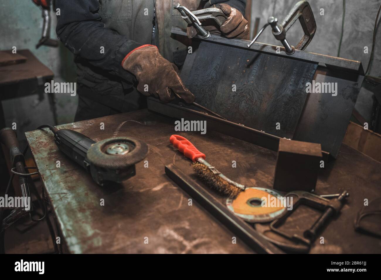 Man clamps iron products into c-clamps. Man works with clamps. Steel ...