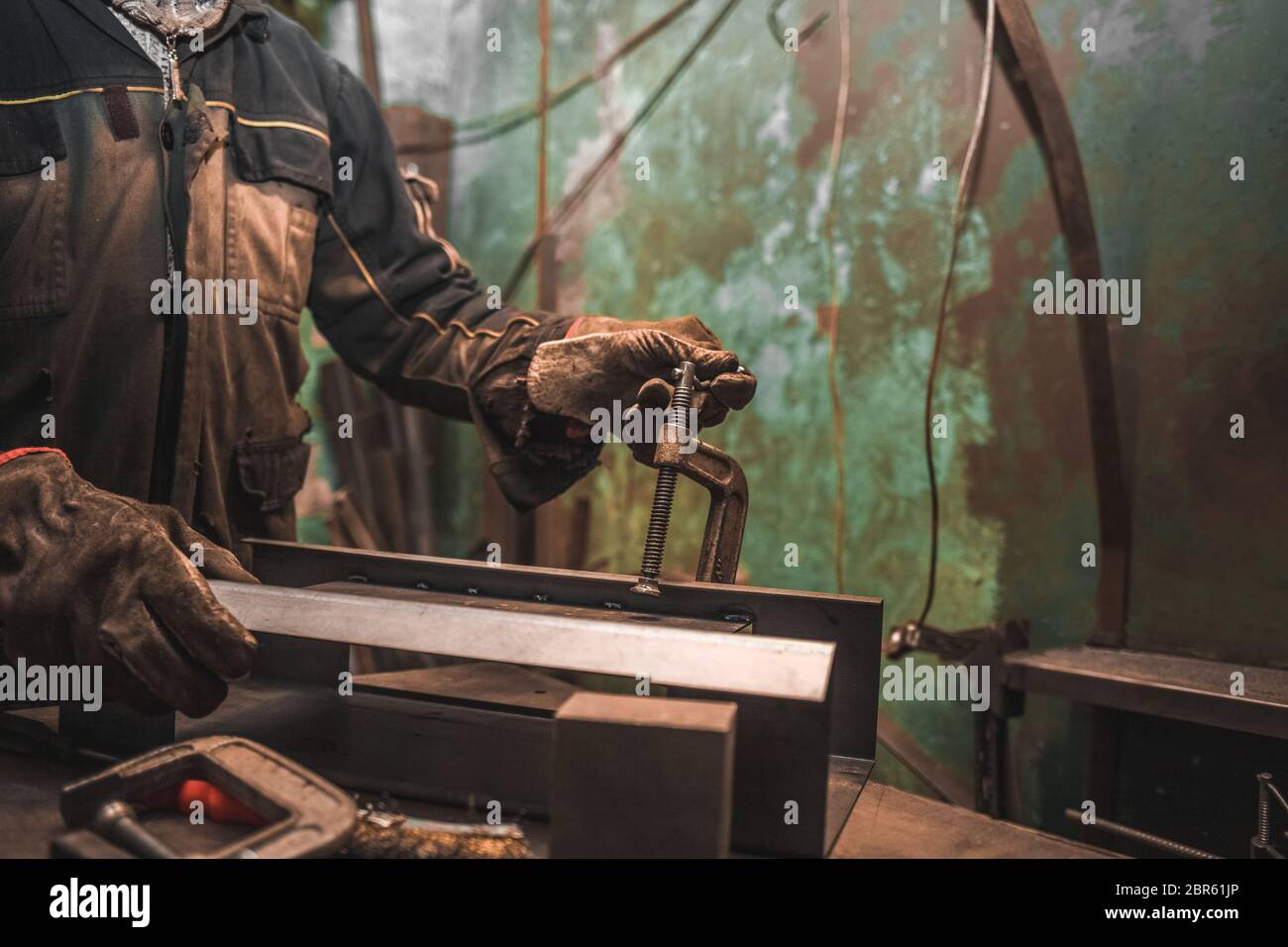 Man clamps iron products into c-clamps. Man works with clamps. Steel ...