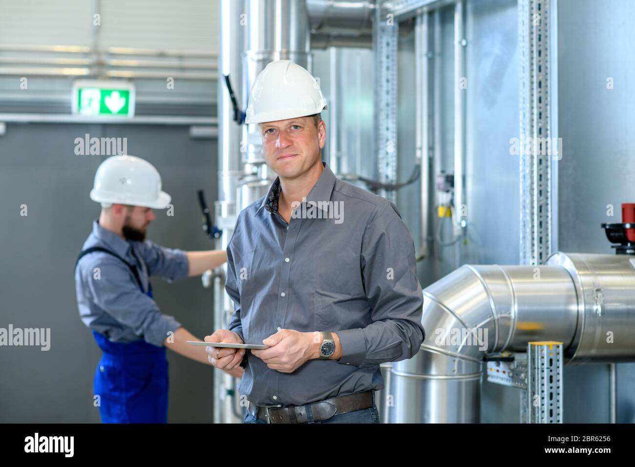 boss with worker in the background in his factory Stock Photo - Alamy