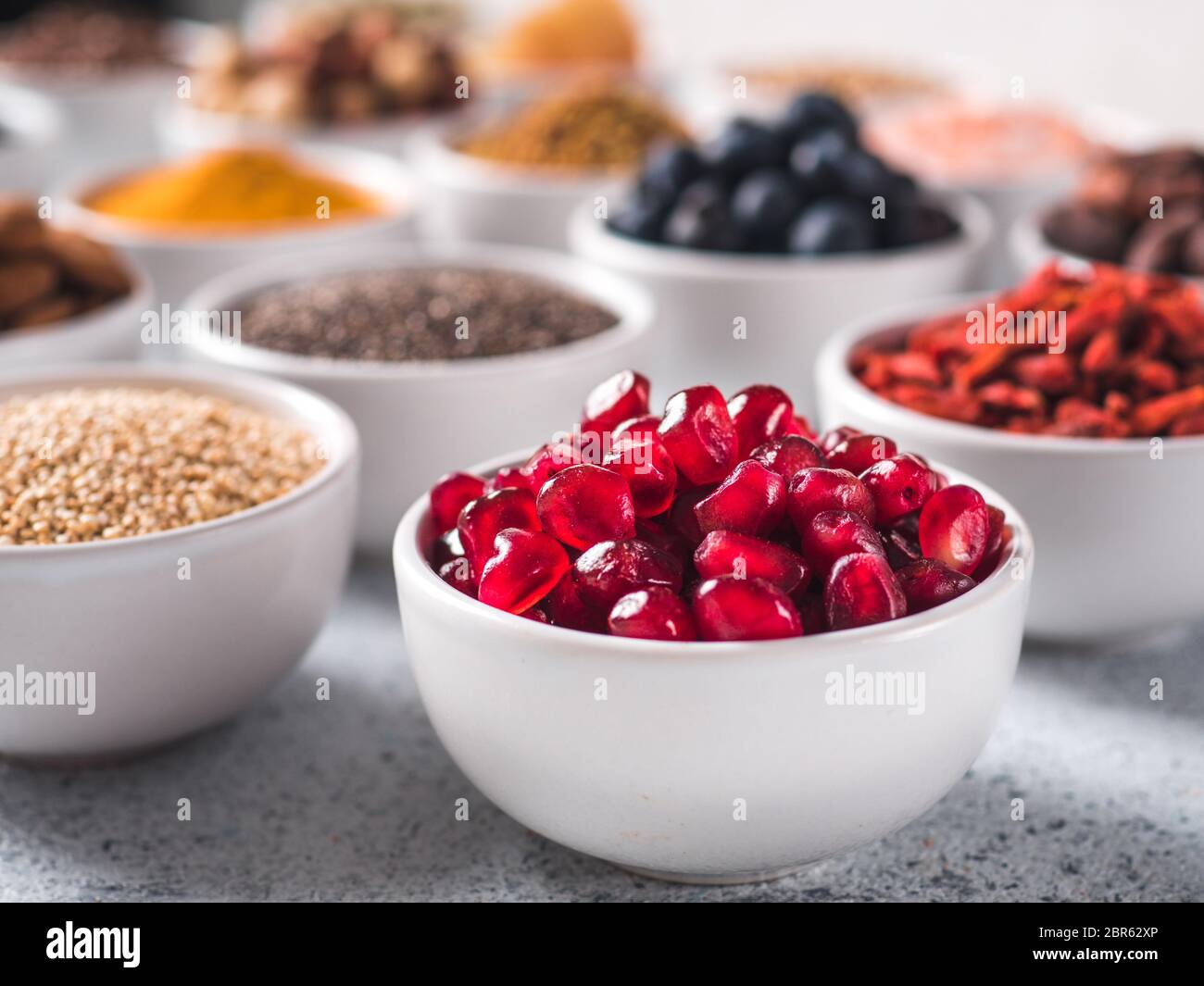 pomegranate or grain of garnet in small white bowl and other superfoods ...