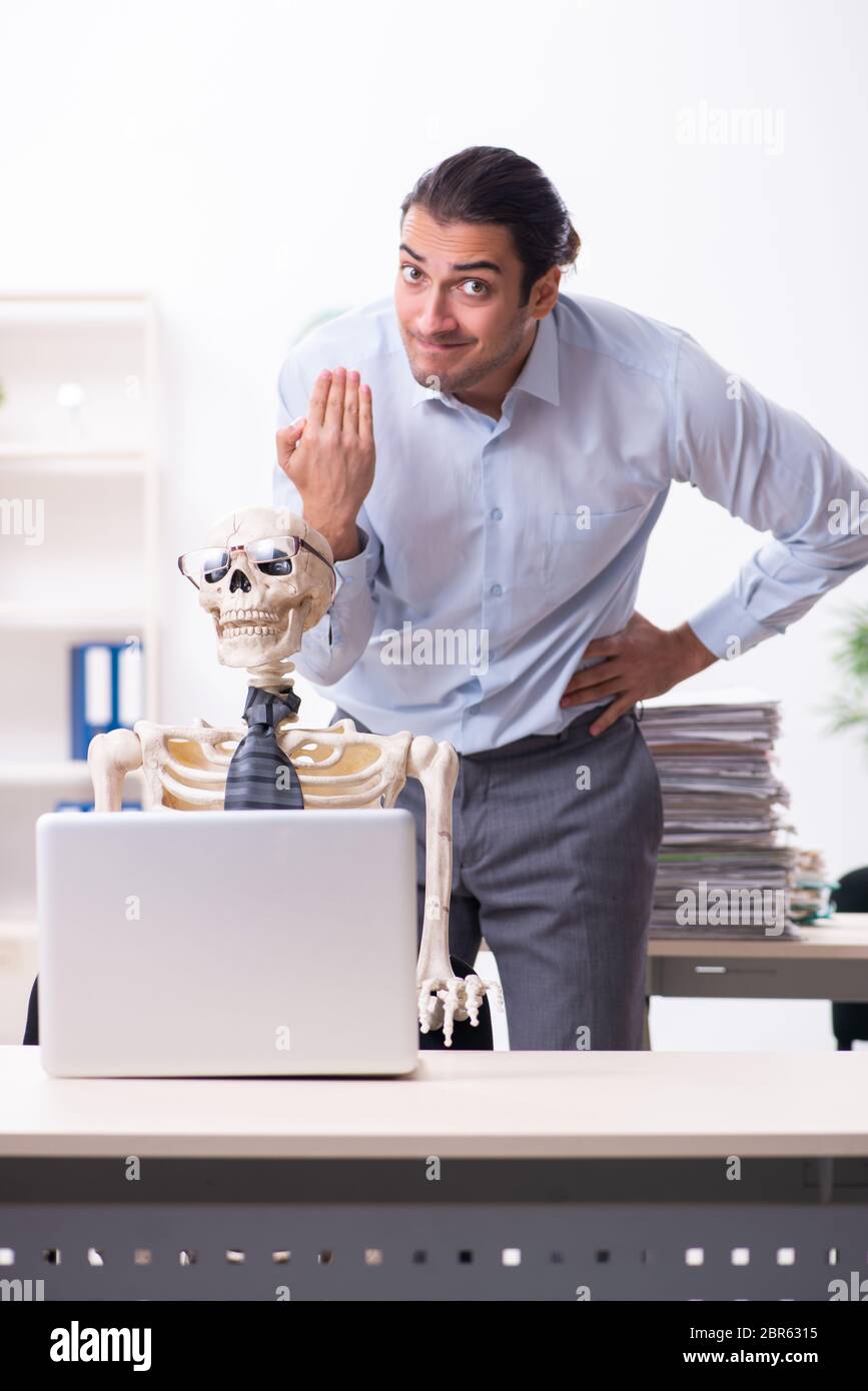 Young employee and skeleton in the office Stock Photo - Alamy