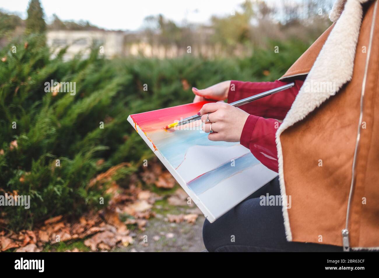 Side view of the painter sitting on a bench and paints a picture Stock ...