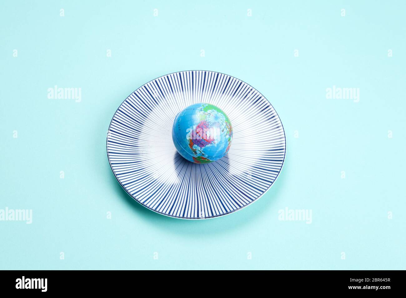 an earth planet ball placed on a target plate on a turquoise background ...