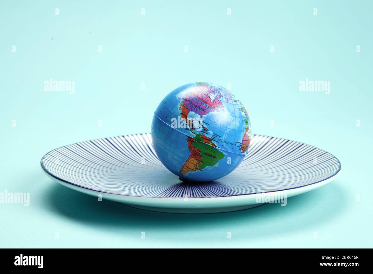 an earth planet ball placed on a target plate on a turquoise background ...