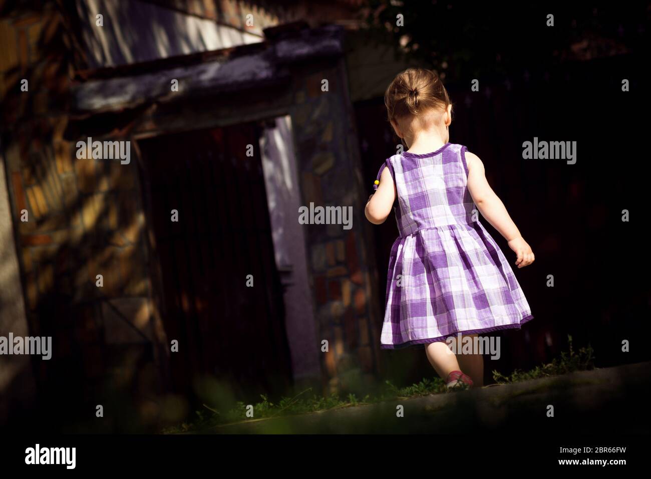 Cute little girl in purple dress is going home from street Stock Photo ...