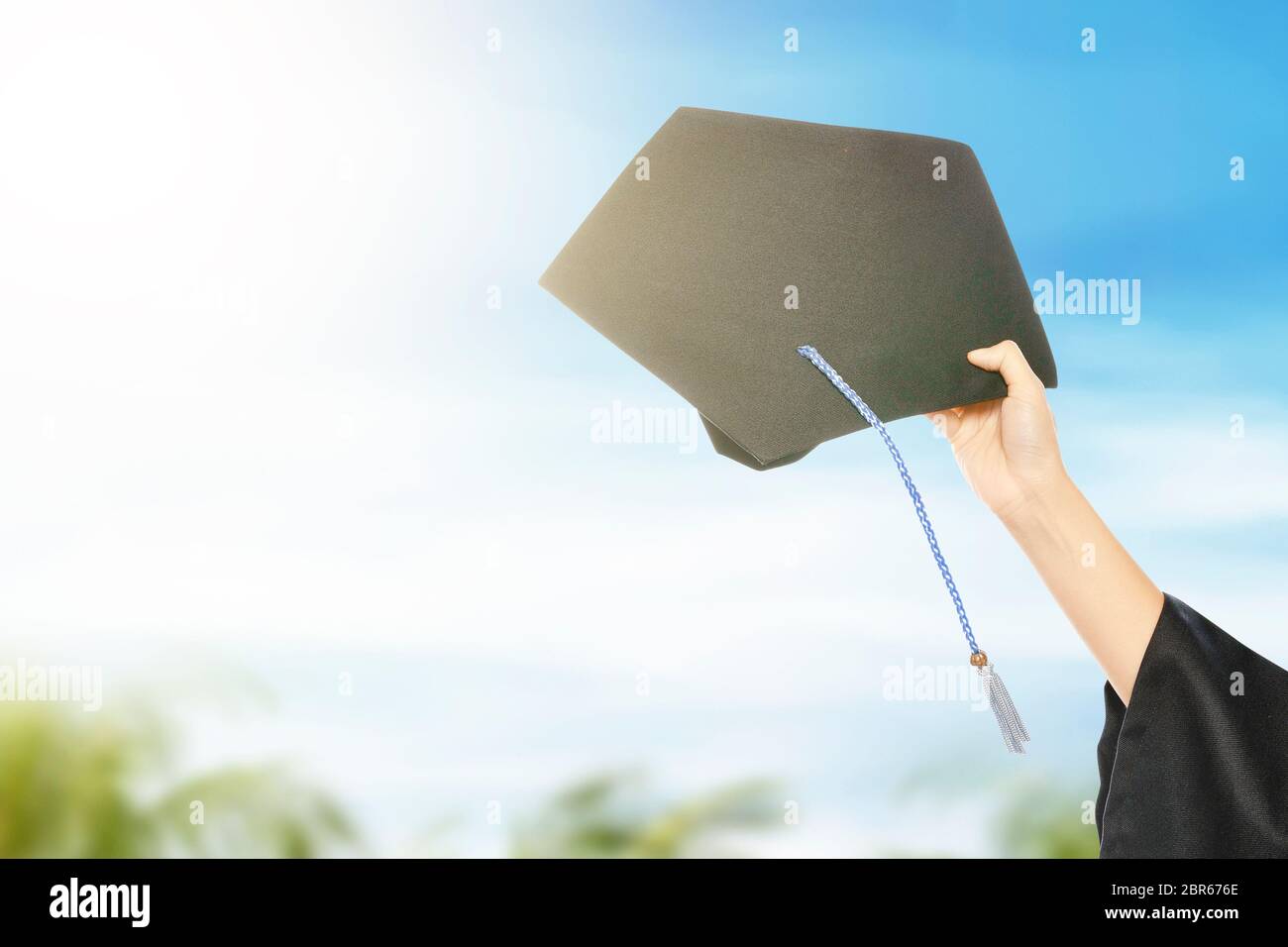Hand holding graduation hat with blue sky background. Graduation ...