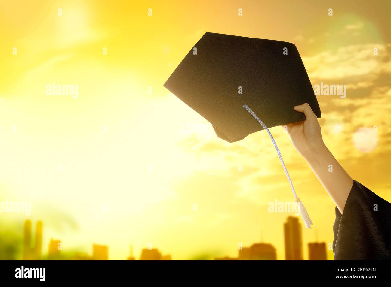 Hand holding graduation hat with sunlight background. Graduation ...