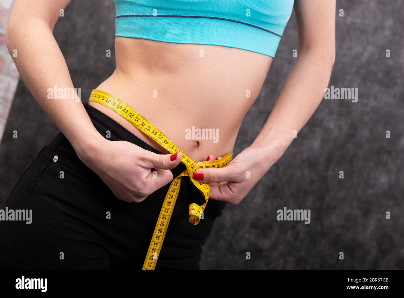 a girl is mesuring her waist with measuring type. Close-up Stock Photo ...