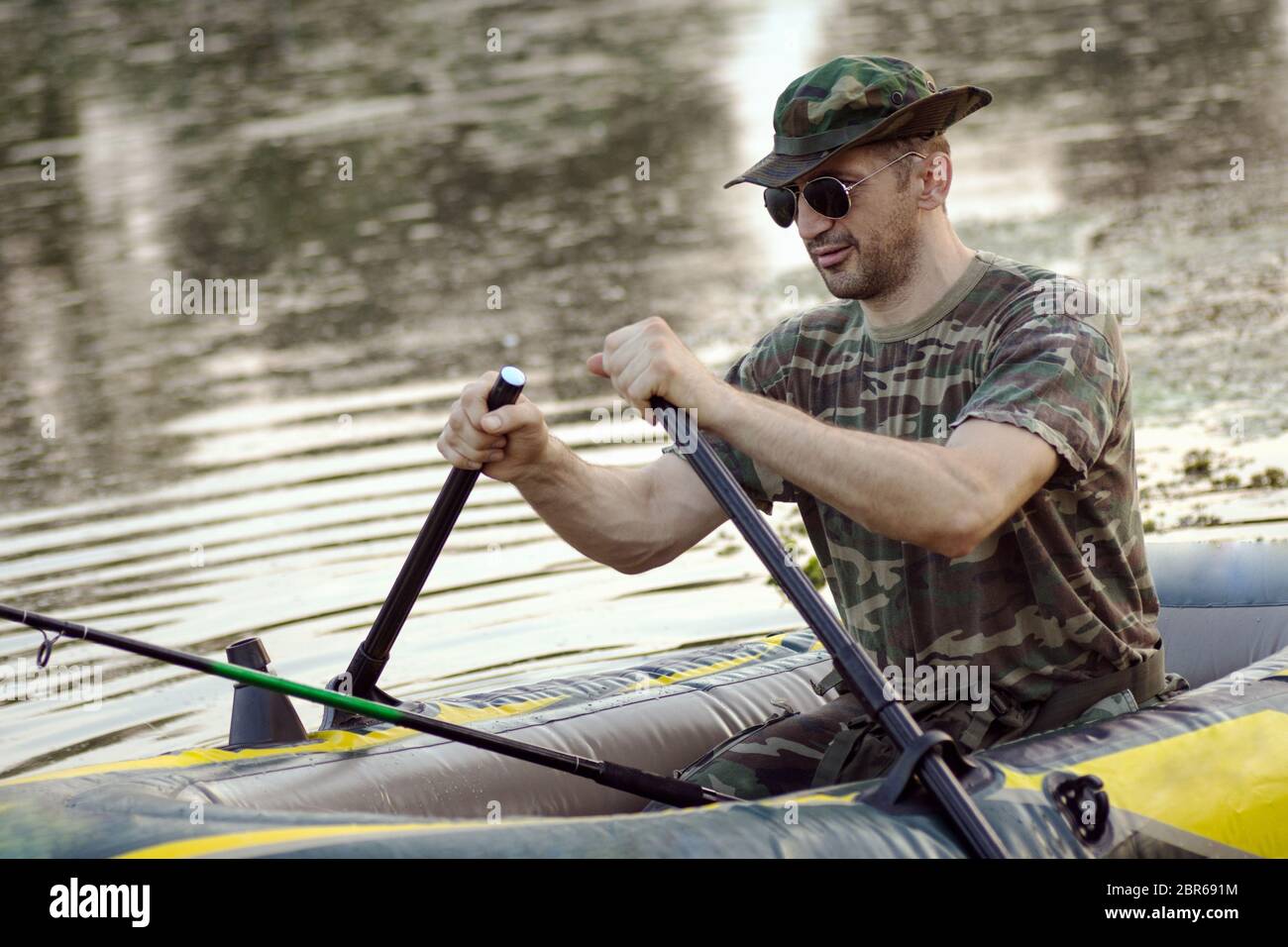 The oarsman is rowing in inflatable boat on the lake Stock Photo - Alamy
