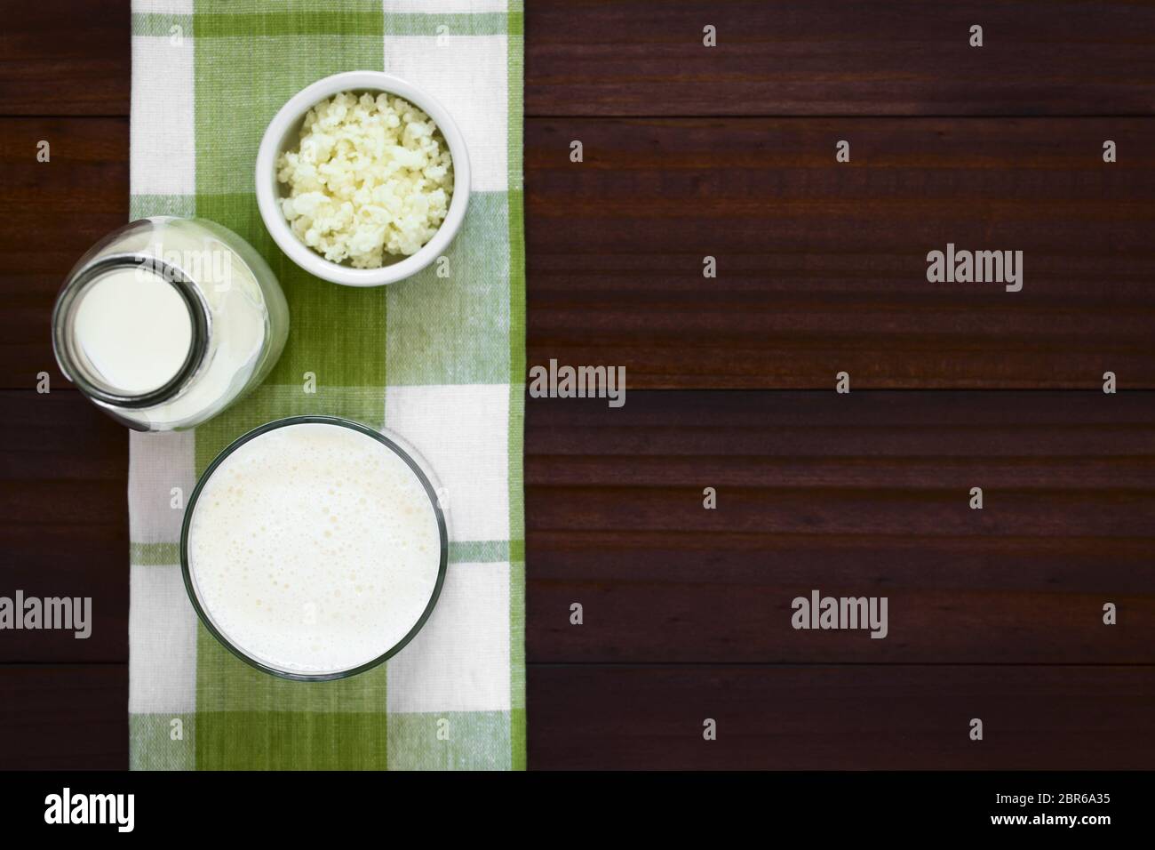 Fresh homemade kefir drink in glass with kefir grains and milk on the ...