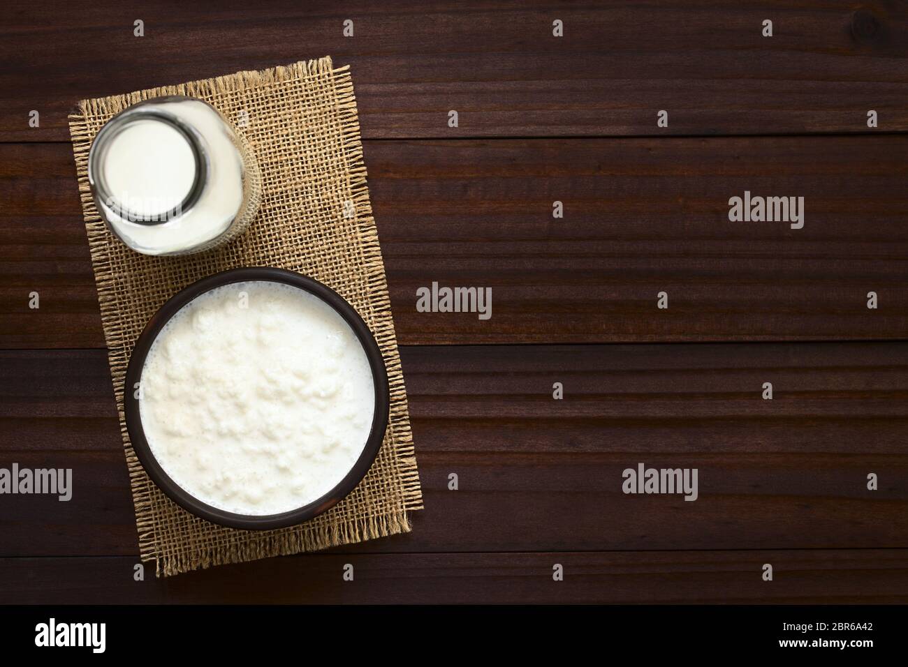 Kefir grains in milk in bowl with bottle of milk on the side ...