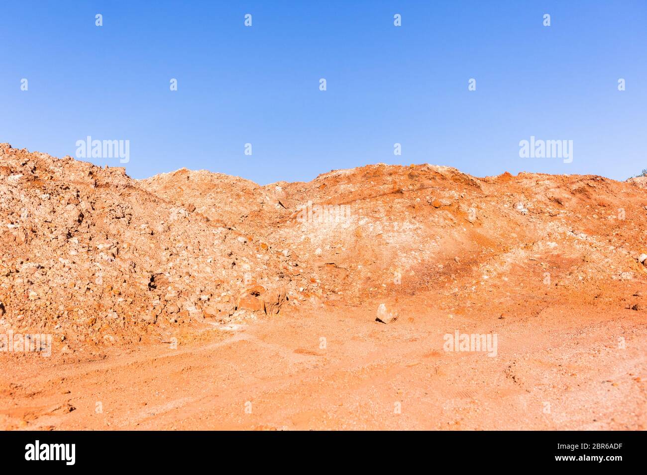 Earthworks mound of sand red color textures against blue sky Stock ...