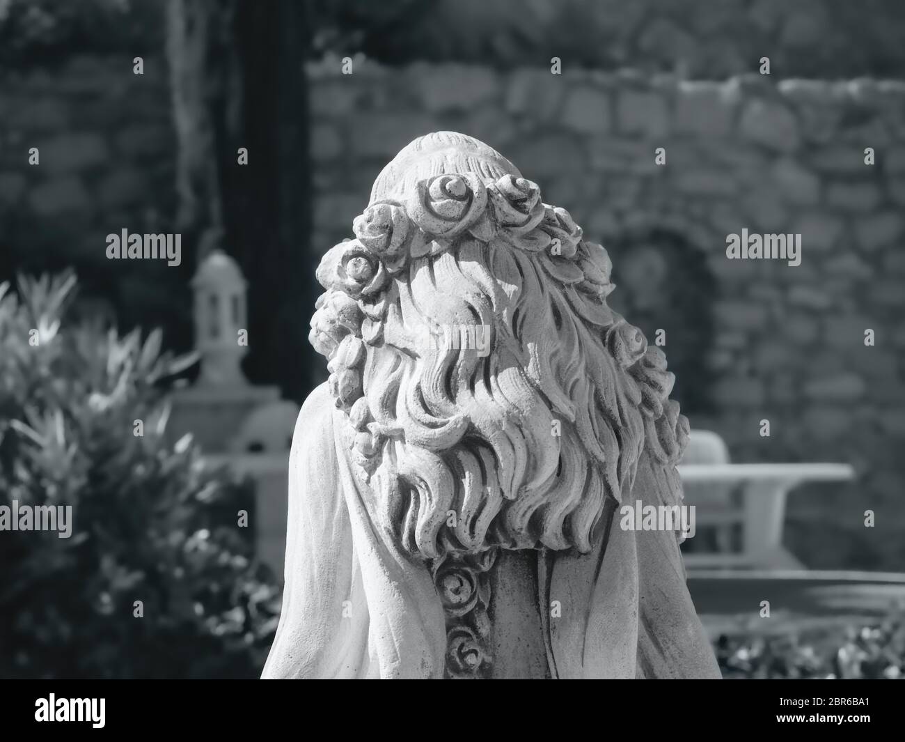 upper back view of a white stone female statue, curly long hair with a ...
