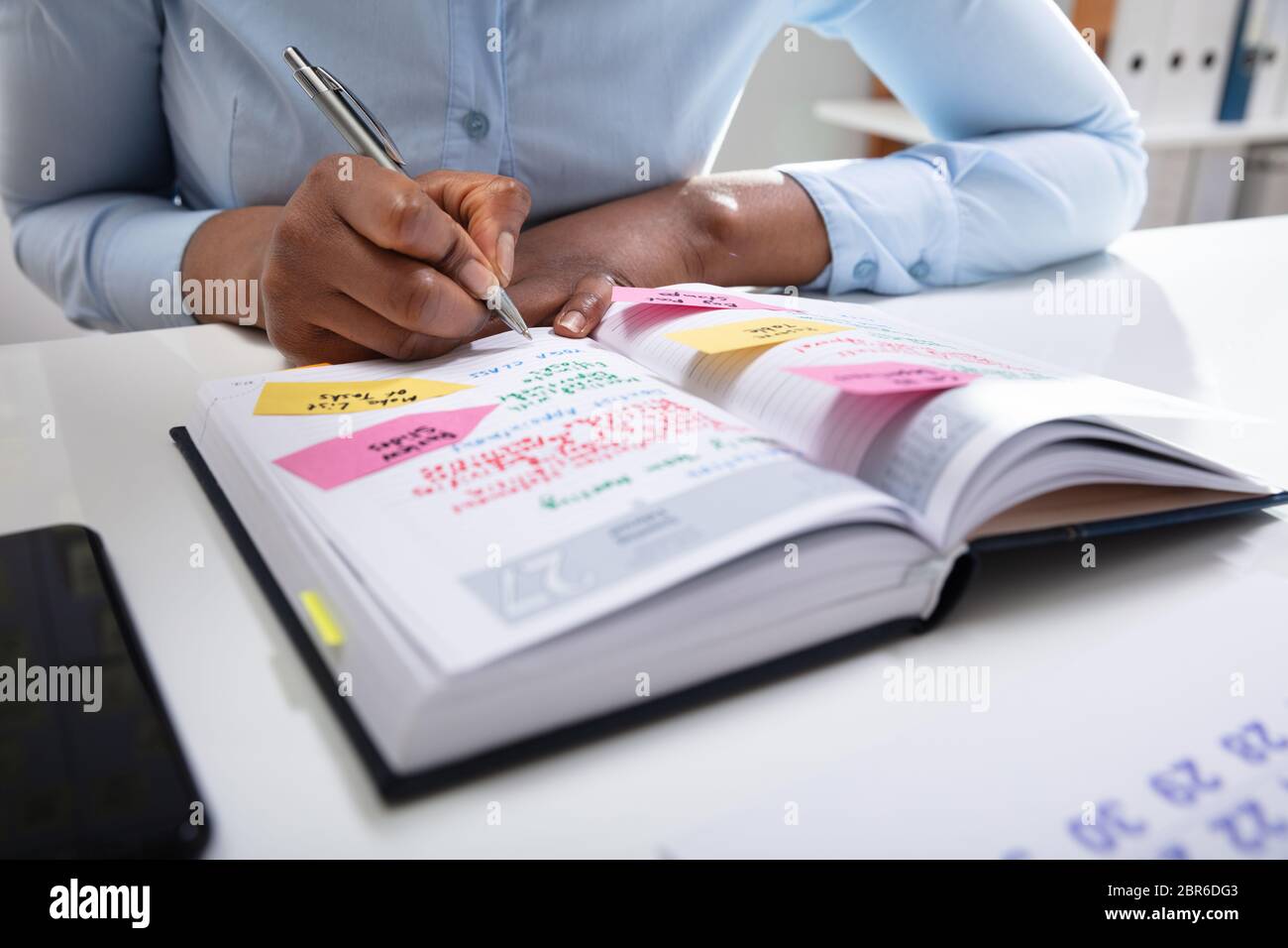 Businesswoman's Hand Checking Schedule In Diary With Calendar On White ...