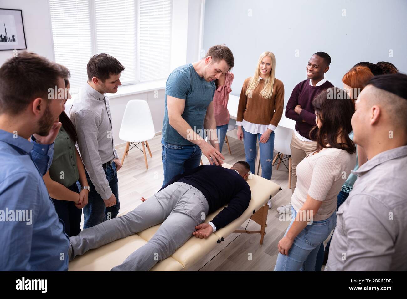 Male Instructor Teaching Massage Technique To Group Of Multi-ethnic ...