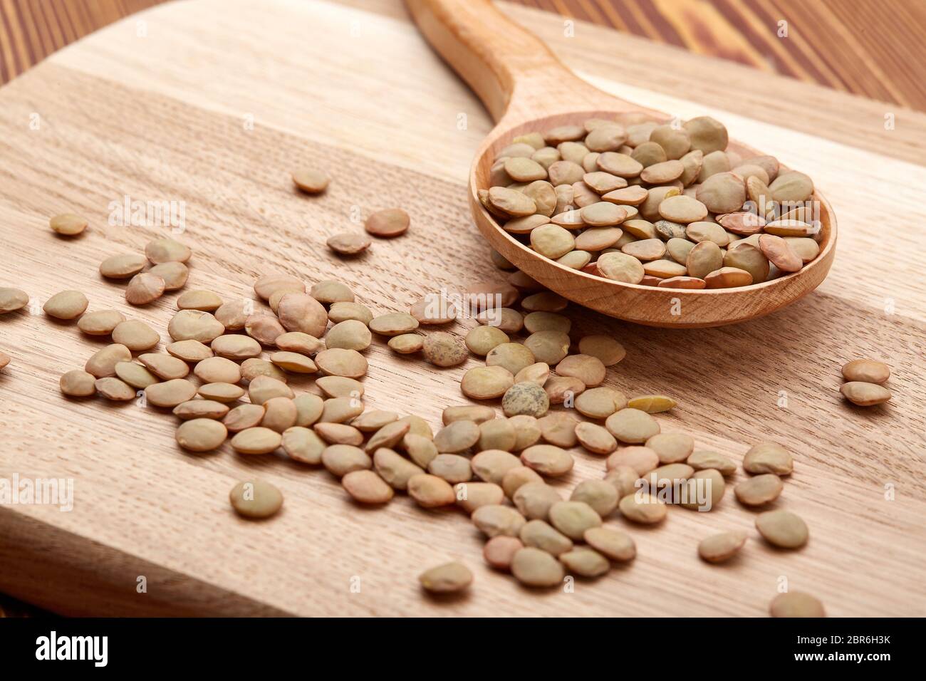 Dry lentils on wooden spoons lying on wooden background. Legumes Stock ...