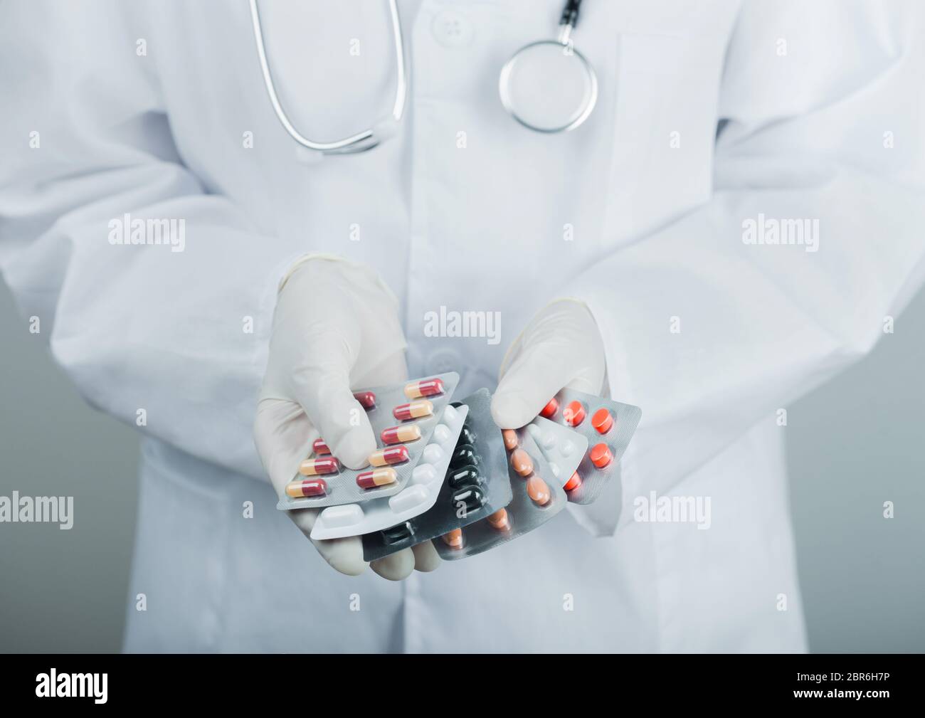 Medical doctor wearing clear latex gloves holding stack of different ...