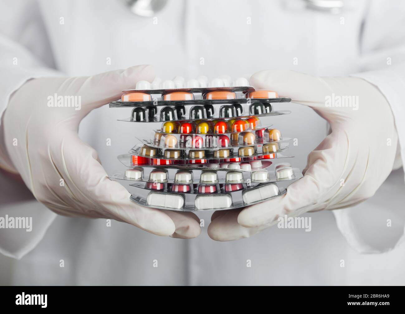Medical doctor wearing clear latex gloves holding stack of different ...