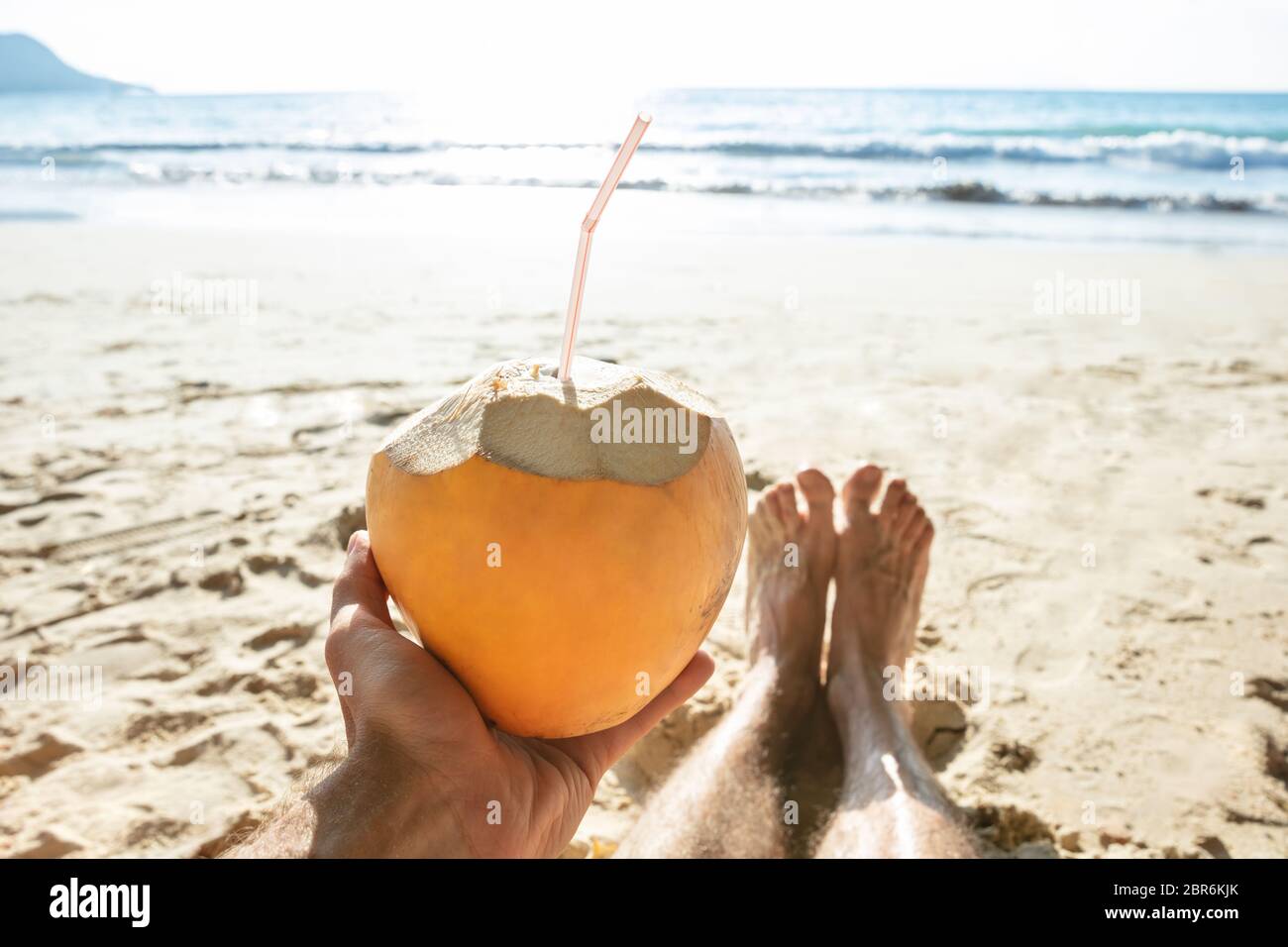 Hand holding coconut on beach hi-res stock photography and images - Alamy