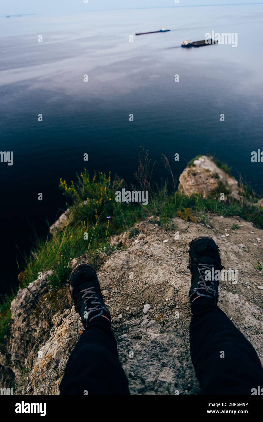 Person sitting on the edge of a cliff Stock Photo - Alamy