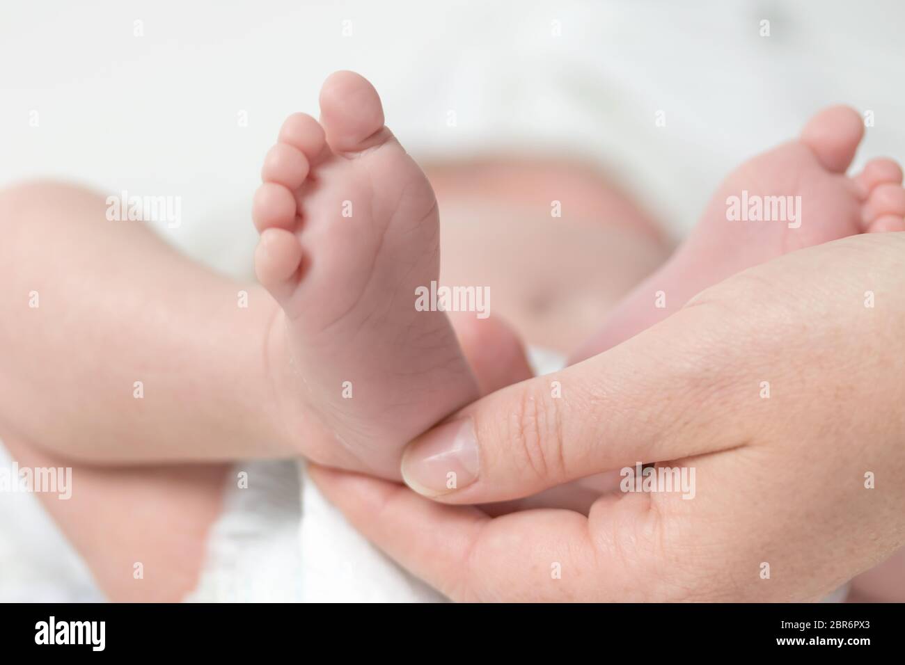 Closeup view of mother's hand holding the feet of her newborn son Stock ...