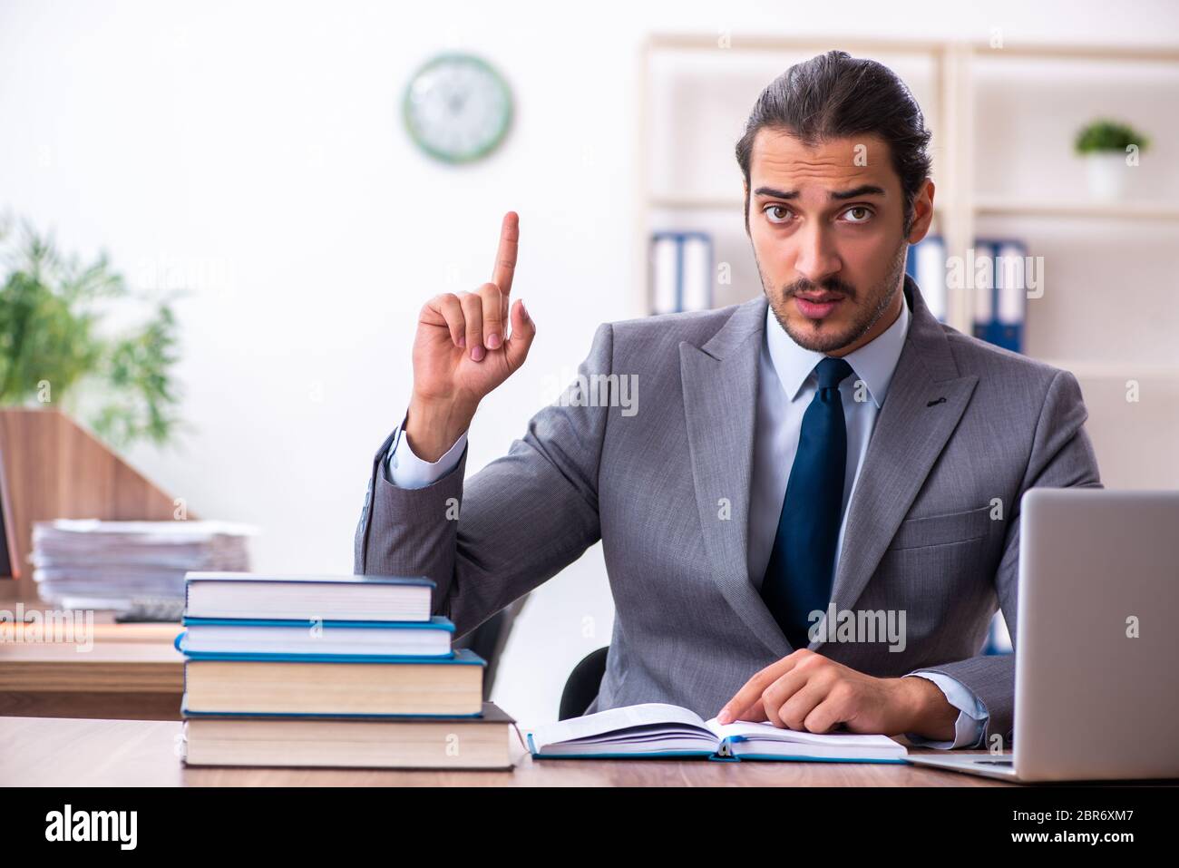 Young businessman reading books at workplace Stock Photo - Alamy