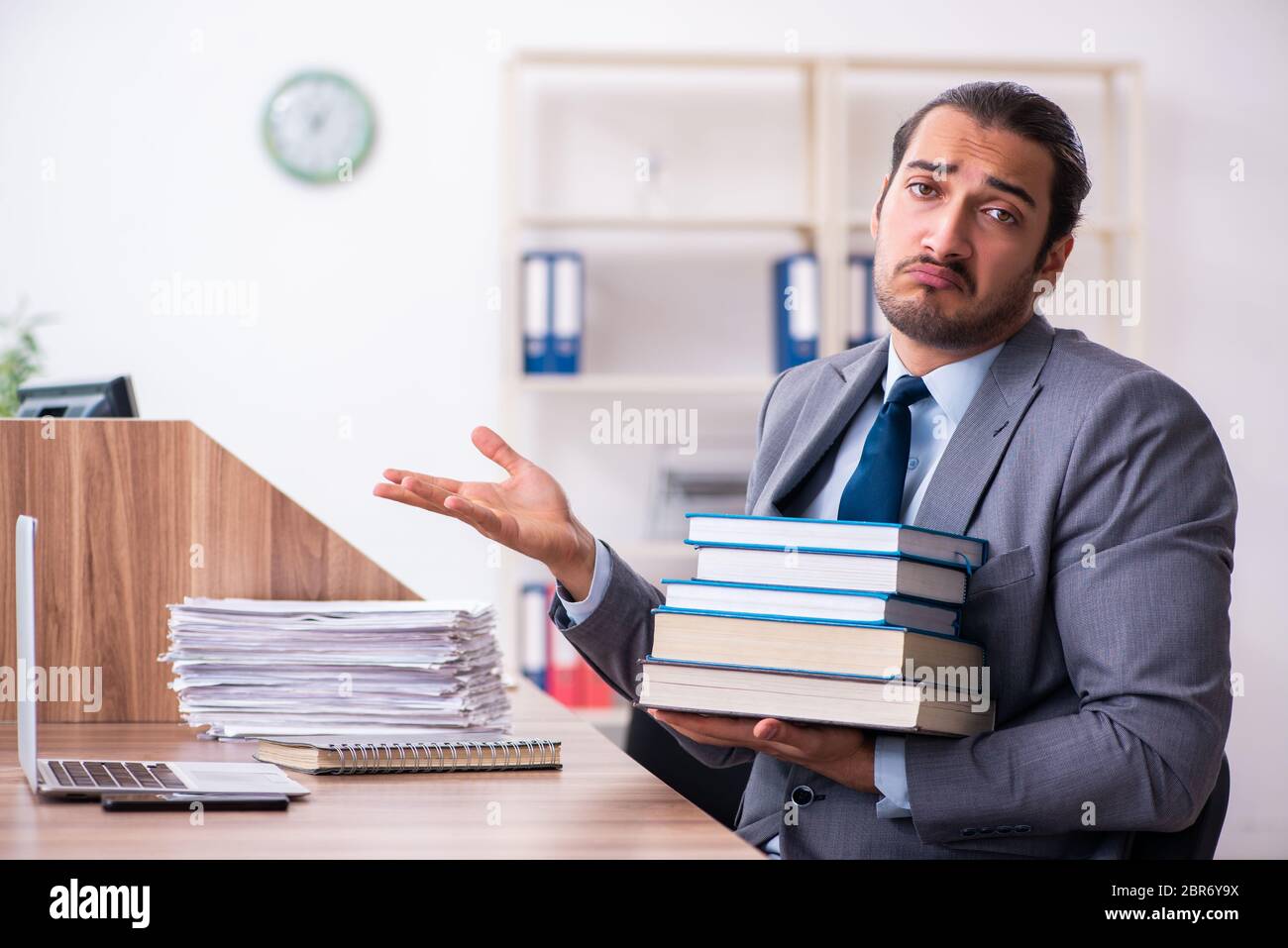 Young businessman reading books at workplace Stock Photo - Alamy