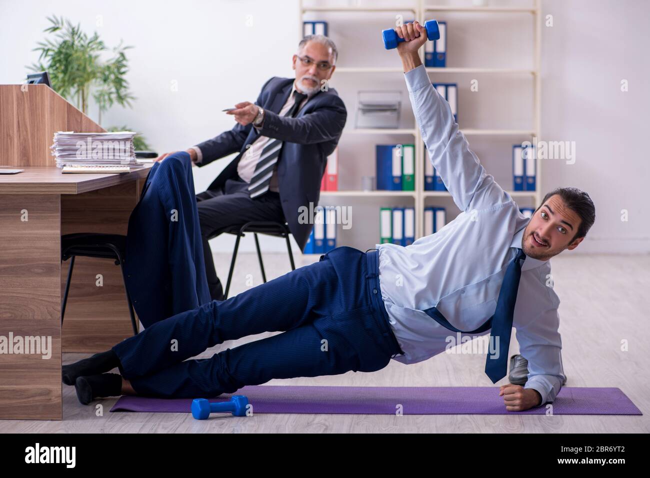 Two employees doing physical exercises at the workplace Stock Photo - Alamy