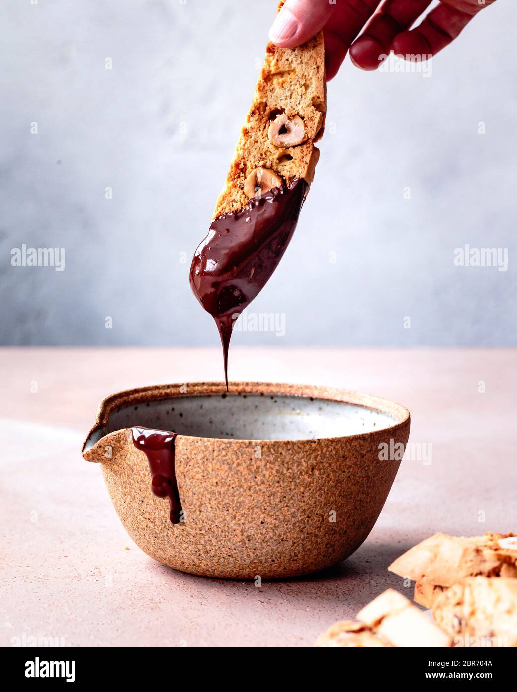 Melted chocolate dripping off a piece of hand held hazelnut biscotti ...