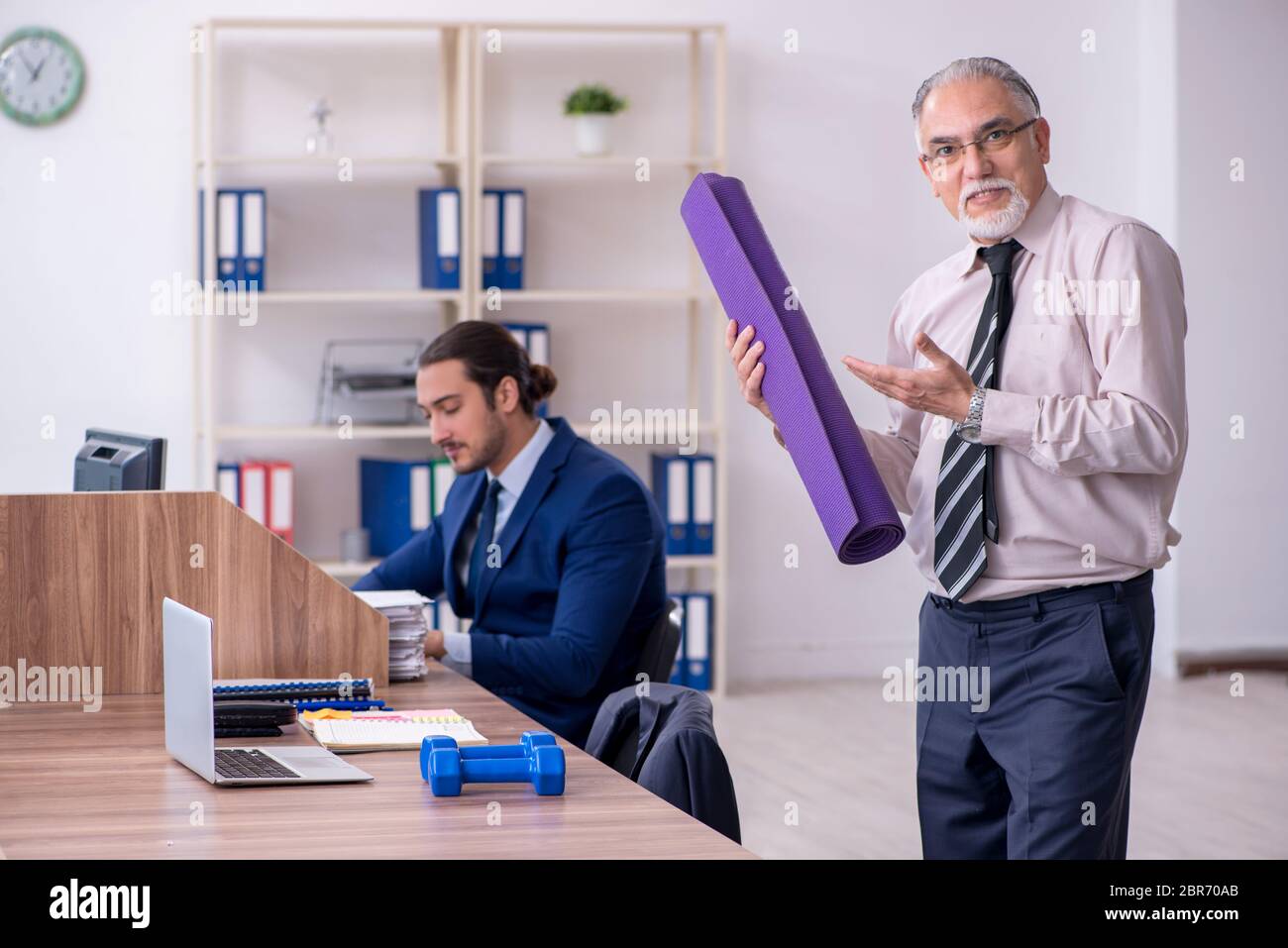 Two employees doing physical exercises at the workplace Stock Photo - Alamy
