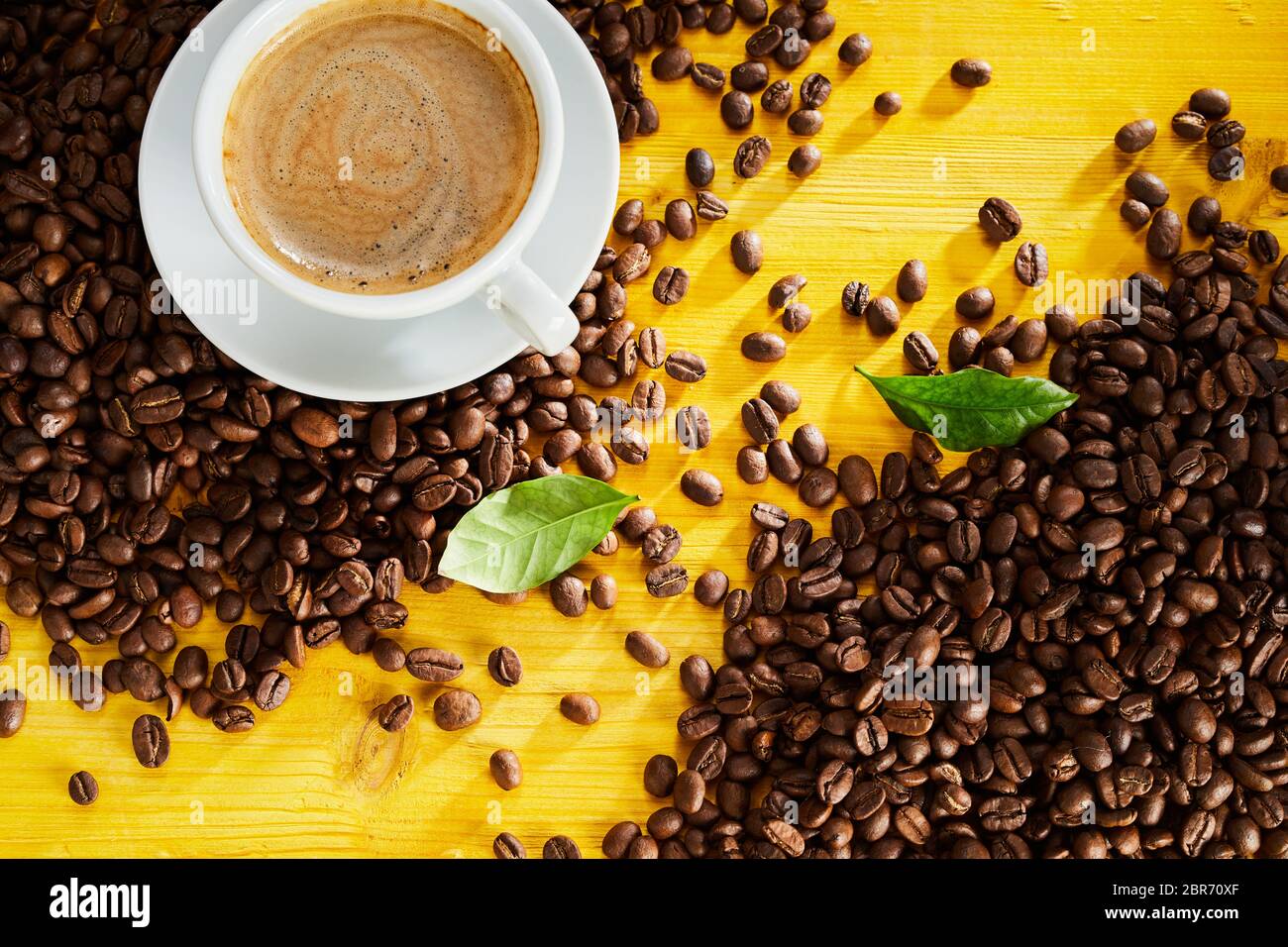 Cup of frothy cappuccino coffee with full roasted beans arranged in two ...