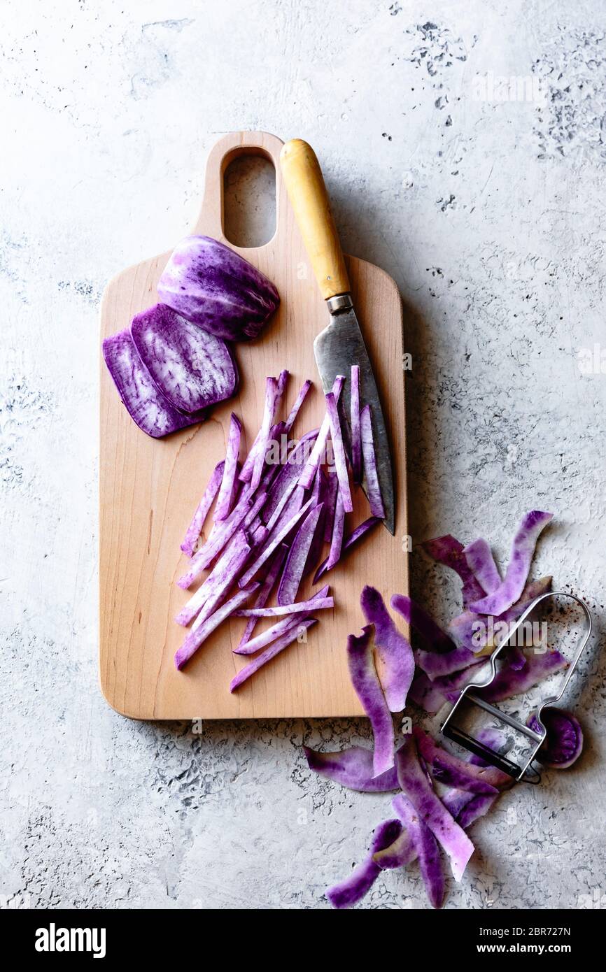 Purple daikon cut into julienne strips on a wooden cutting board Stock ...