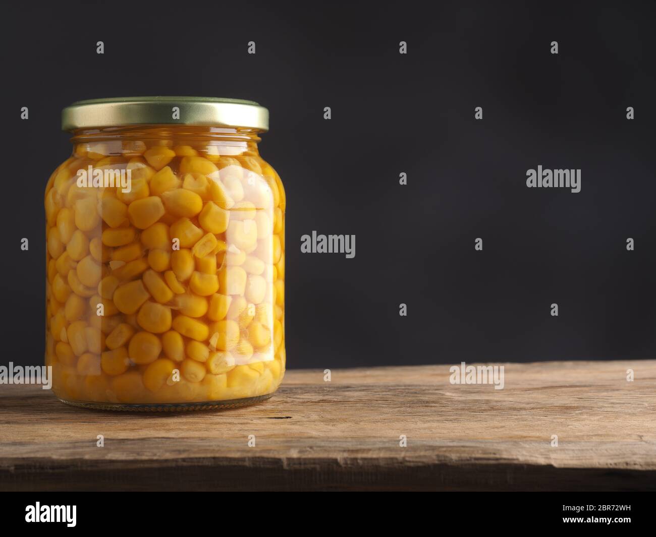 Organic corn in a mason jar on a rustic wooden table with space for ...