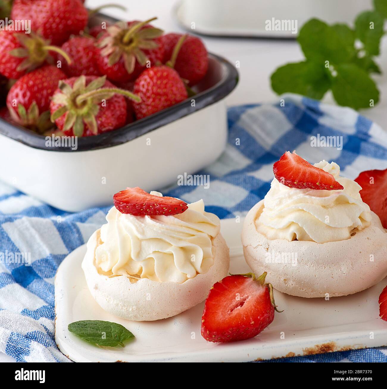 baked meringue with cream and fresh strawberries, behind the tray with ...