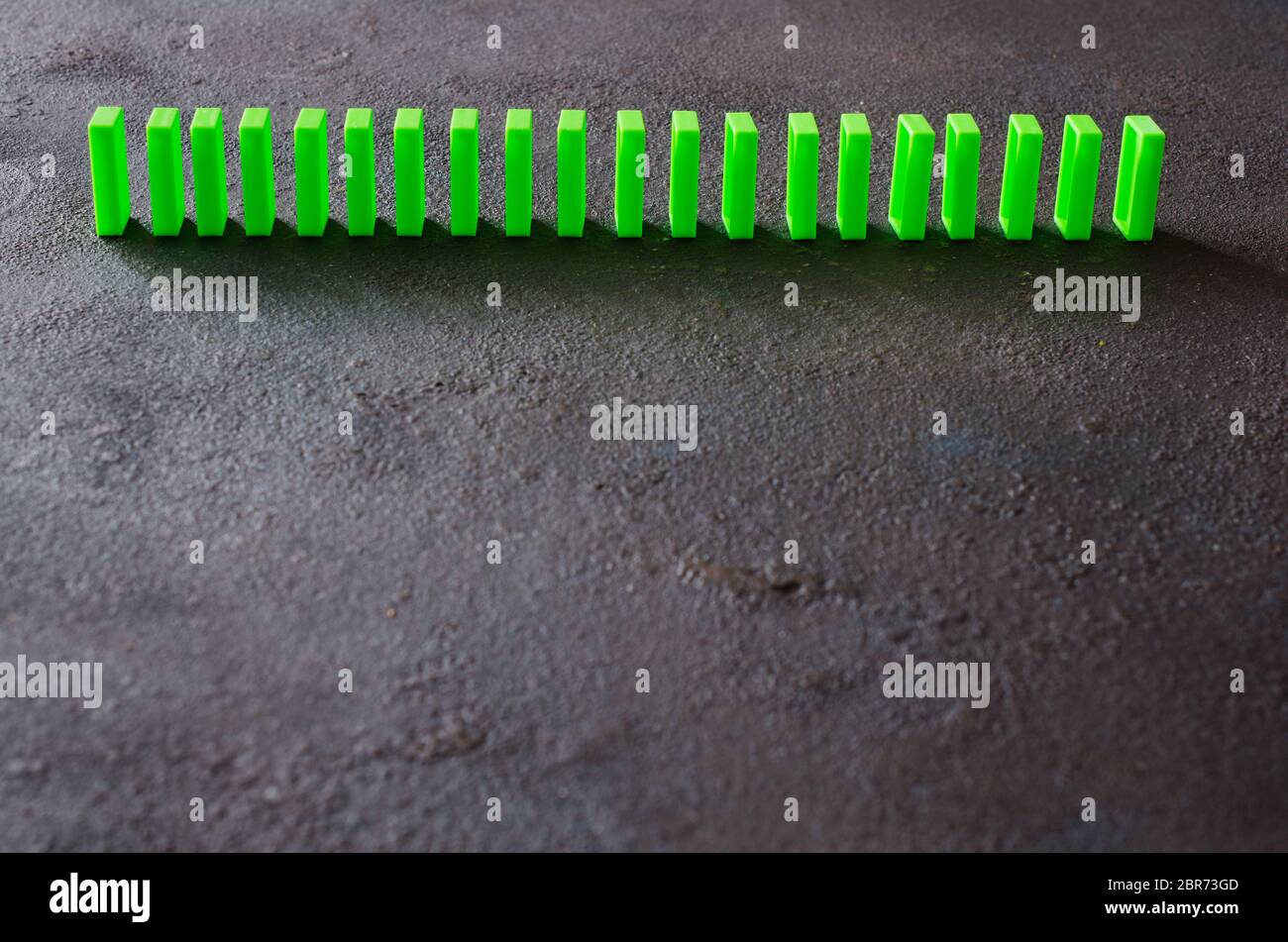 Domino effect. Row of green dominoes on dark background. Copy space ...